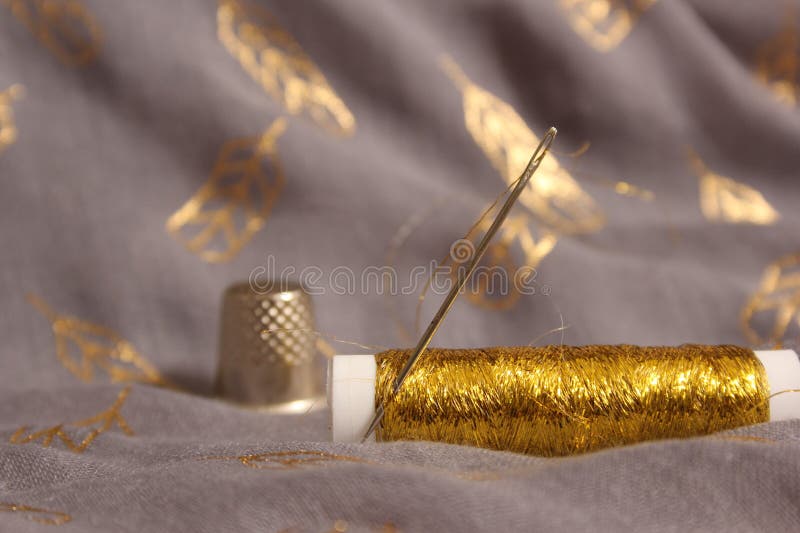 Spool of Metallic Gold Thread on Gray and Gold Chiffon Fabric Stock ...
