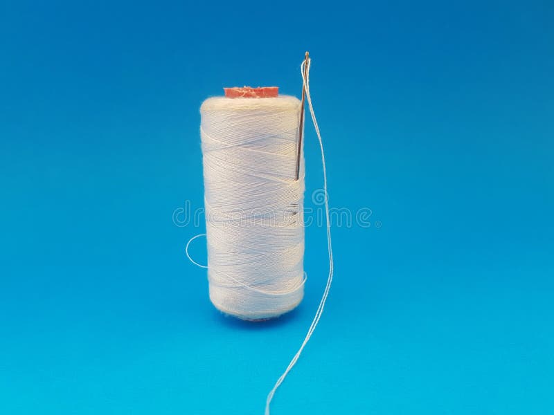 A Spool of Old and Used Sewing Thread in White on a Blue Background ...