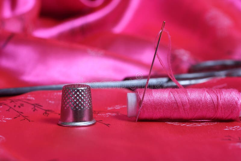 Spool of Pink Thread and Thimble on Vintage Pink Satin Fabric Stock ...