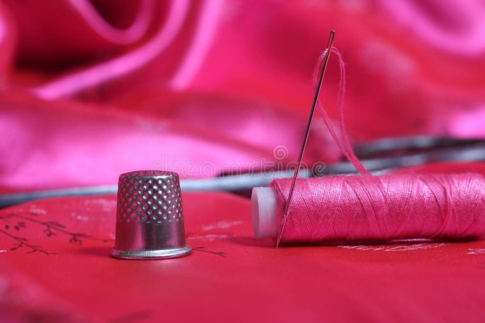 Spool of Pink Thread and Thimble on Vintage Pink Satin Fabric Stock ...