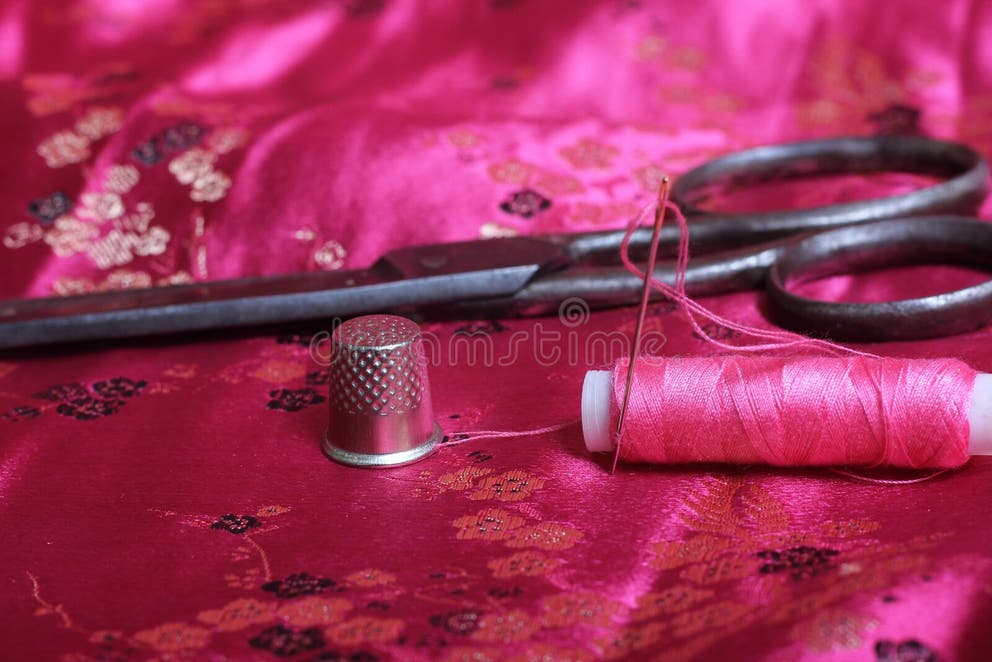 Spool of Pink Thread and Thimble on Vintage Pink Satin Fabric Stock ...
