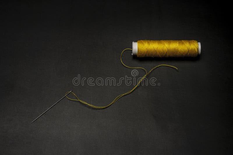 A Needle with Yellow Thread Threaded Together with a Spool of the Same ...