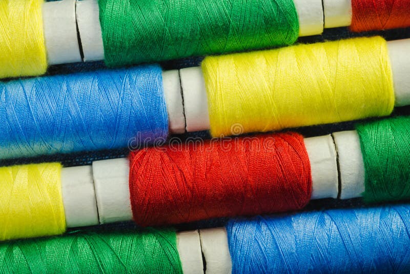 Spools of Blue, Yellow, Red and Green Sewing Thread Arranged in Rows on ...