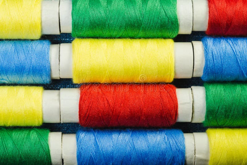 Spools of Blue, Yellow, Red and Green Sewing Thread Arranged in Rows on ...