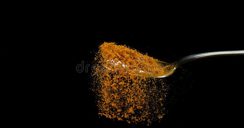 Spoon and Curry Powder Falling from Spoon Against Black Background ...