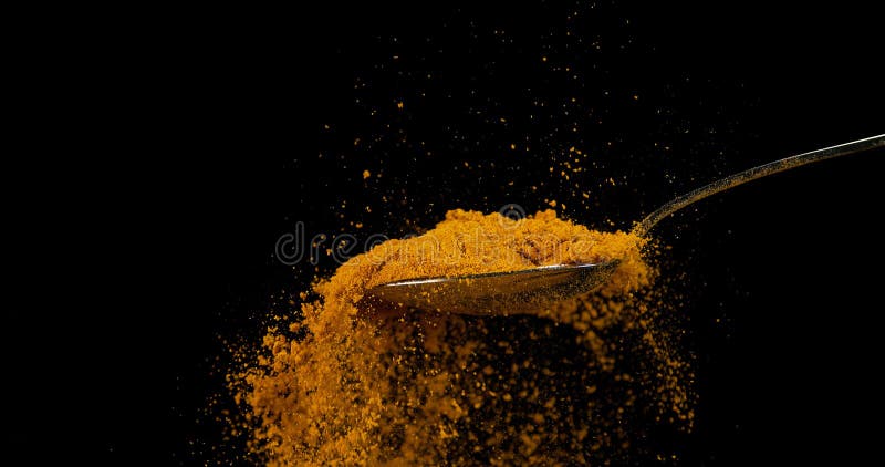Spoon and Curry Powder Falling from Spoon Against Black Background ...