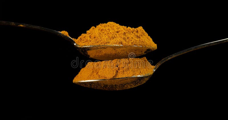 Spoon and Curry Powder Falling from Spoon Against Black Background ...