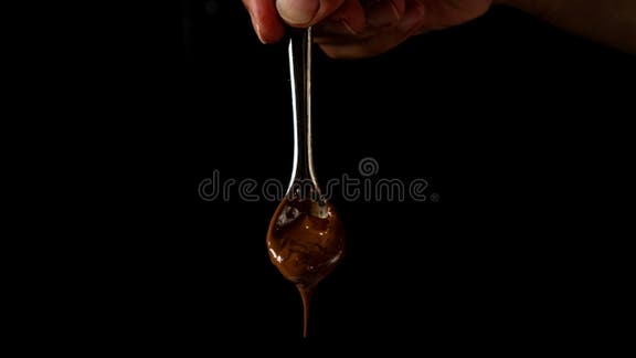 Spoon with Dripping Melted Chocolate Held by Hand on Black Background ...