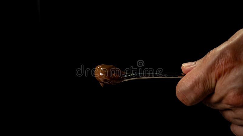 Spoon with Dripping Melted Chocolate Held by Hand on Black Background ...