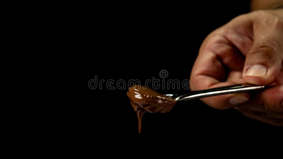 Spoon with Dripping Melted Chocolate Held by Hand on Black Background ...