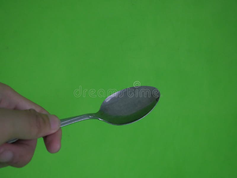 Spoon with a Green Background that is Held by the Hand. Stock Image ...