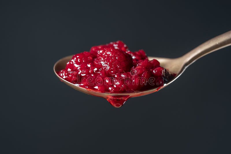 Thick Red Raspberry Jam Dripping from the Spoon, One Drop, on Black ...