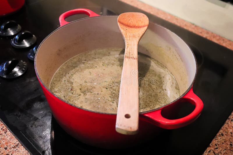 A Spoon Resting on Top of a Pot with Soup Boiling in it Stock Photo ...