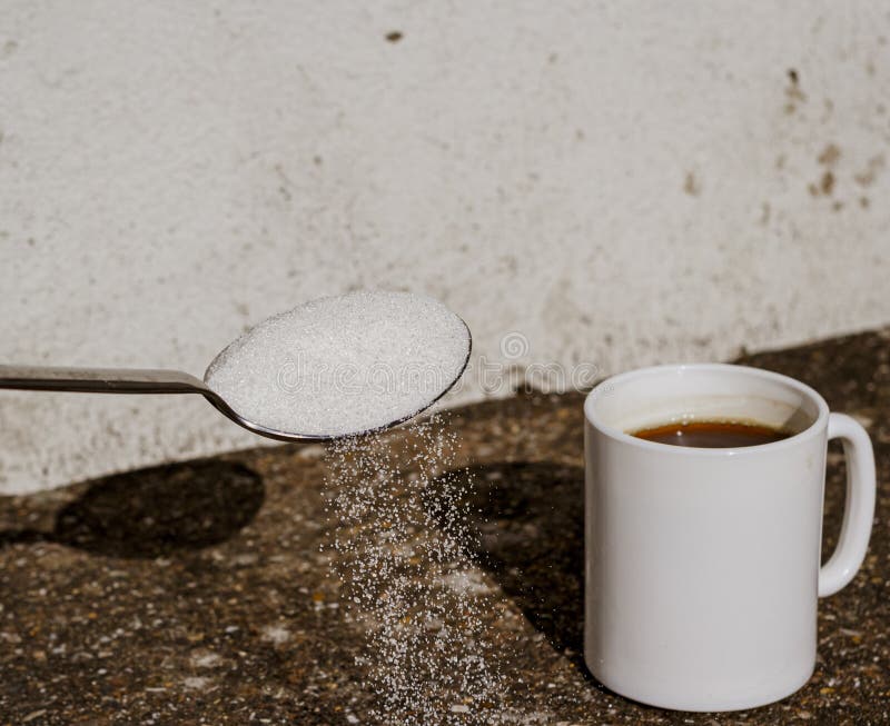 Spoonful of Sugar with Grains of Sugar Falling As Spoon Goes Toward a ...