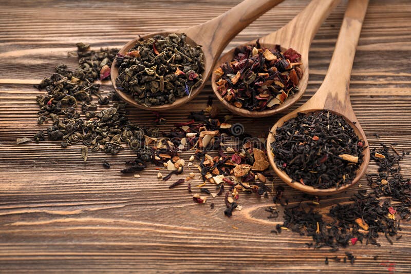 Spoons with Different Types of Dry Tea Leaves on Wooden Background ...