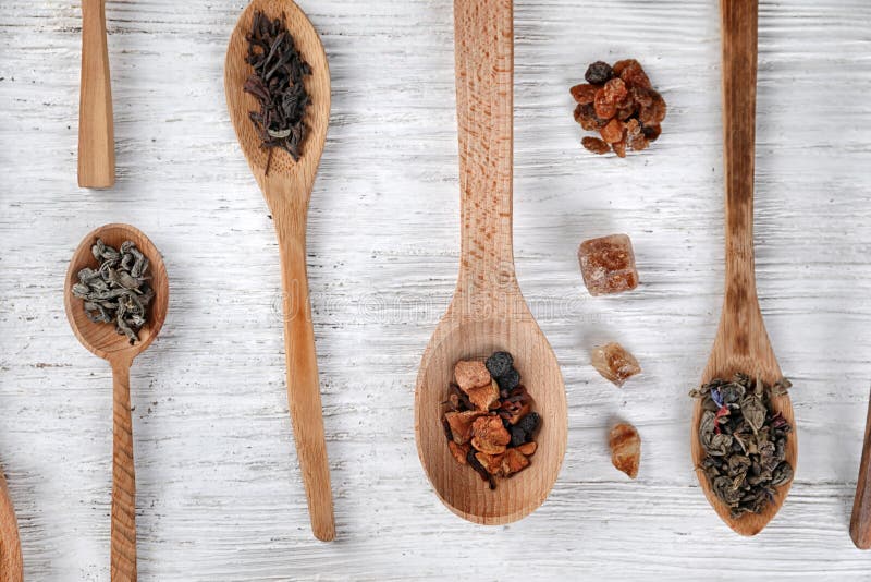 Spoons with Different Types of Dry Tea Leaves on Wooden Background ...