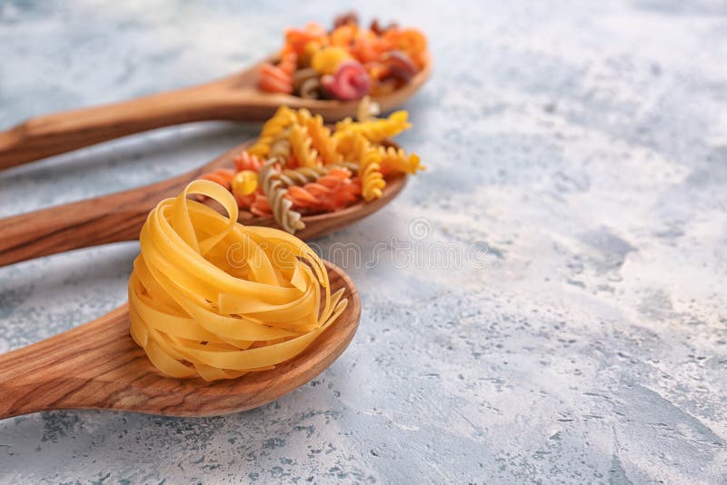 Spoons with Different Types of Raw Pasta on Color Table Stock Image ...