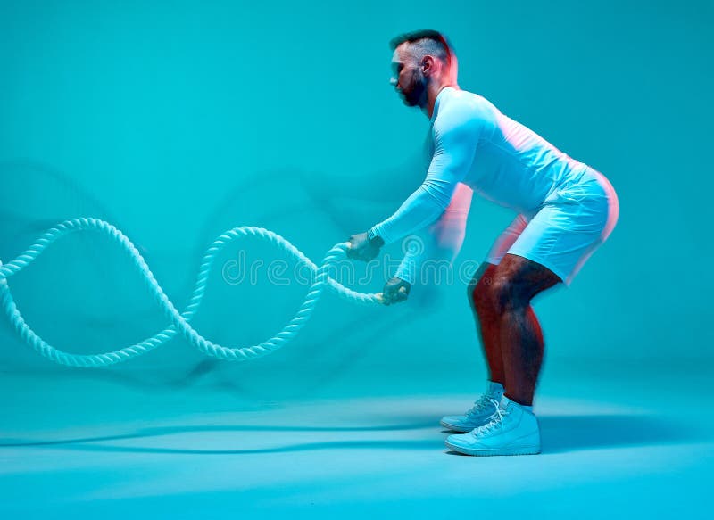 Sportive Modern Guy Training Makes Exercise with Ropes on Blue Studio ...