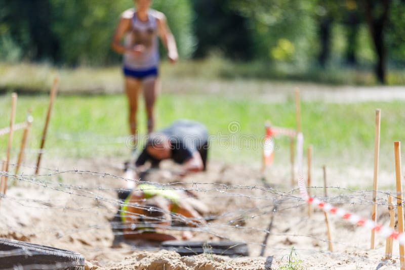 Sportsmen Crawling Under Barbed Wire Obstacle on Their Course in ...