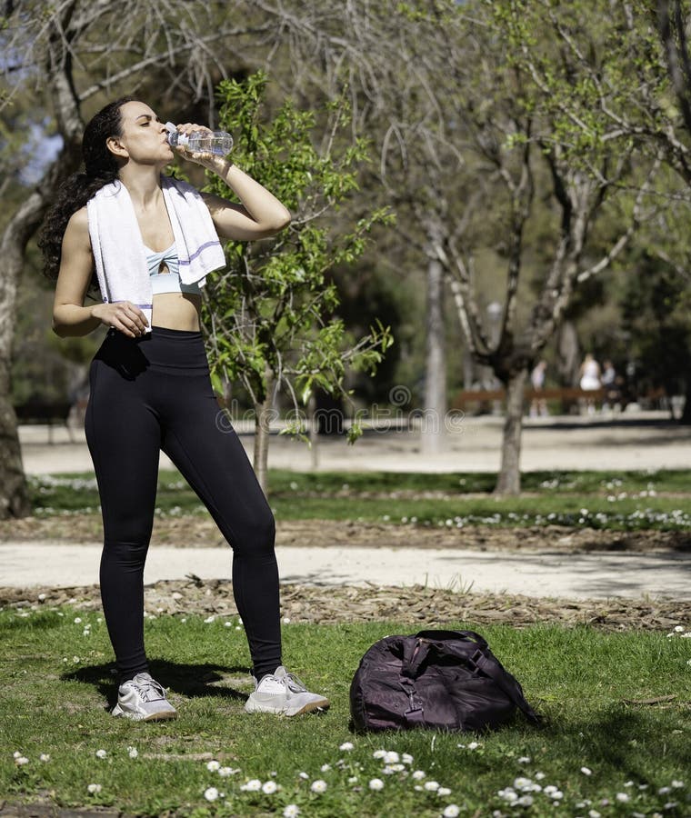 Sportswoman Drinking from a Bottle of Water in a Park after Training ...