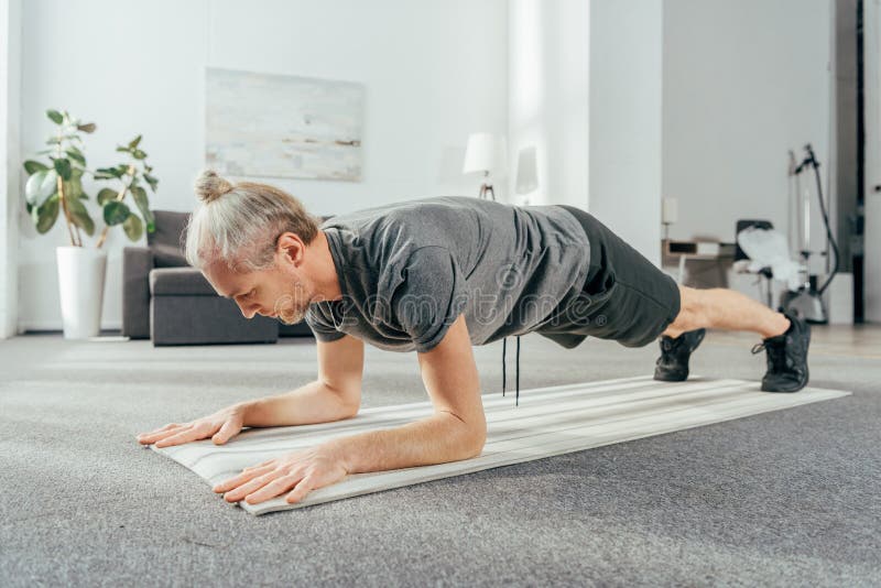 Sporty Adult Man In Sportswear Doing Plank Exercise On Yoga Mat Stock