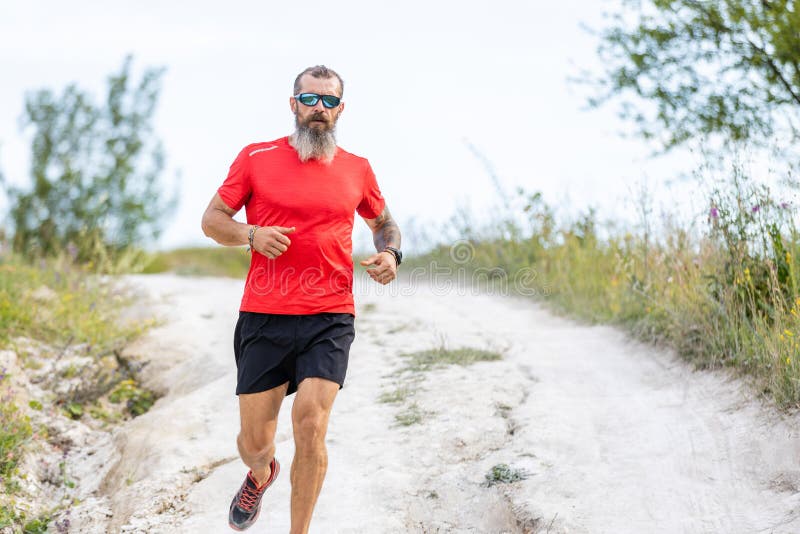 Sporty Bearded Man Running on the Path at Hillside Stock Photo - Image ...
