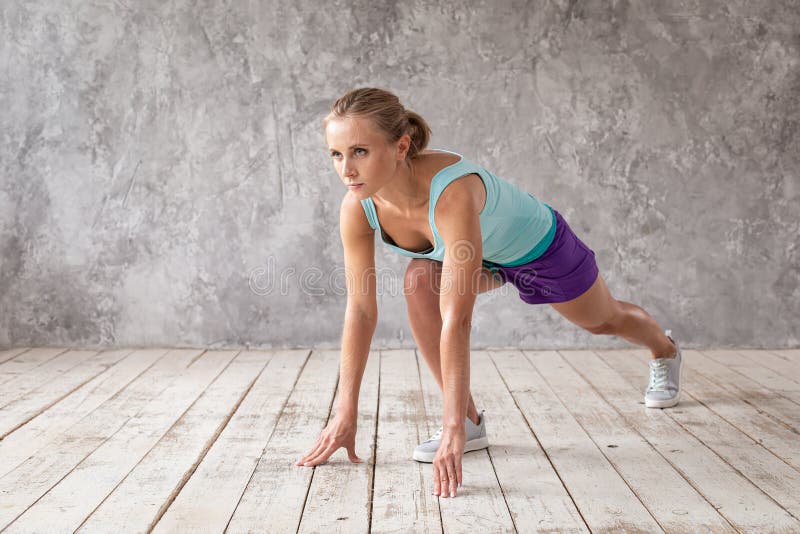 Sporty Blond Woman Doing Lunges with Her Arms Touching Wooden Floor ... Sporty Blond Woman Doing Lunges with Her Arms Touching Wooden Floor ...