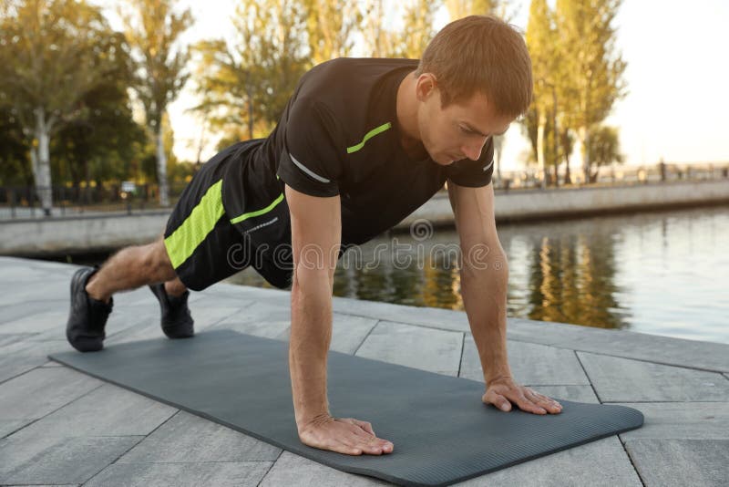 Sporty Man Doing Straight Arm Plank Exercise Near River Stock Image