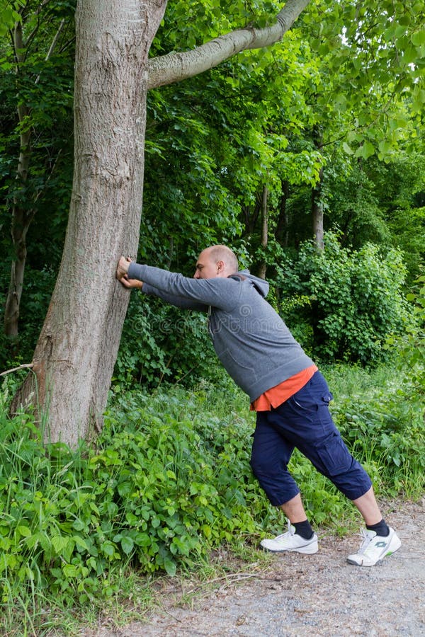 Sporty Man Doing Stretching Exercises in the Forest on a Tree Stock ...