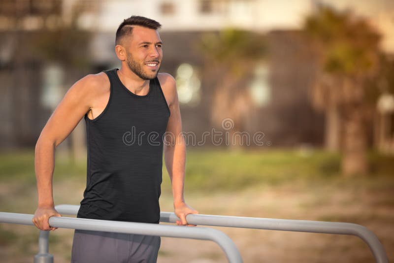 Sporty Young Man Doing Triceps Dips on Parallel Bars Outdoors. Doing ...
