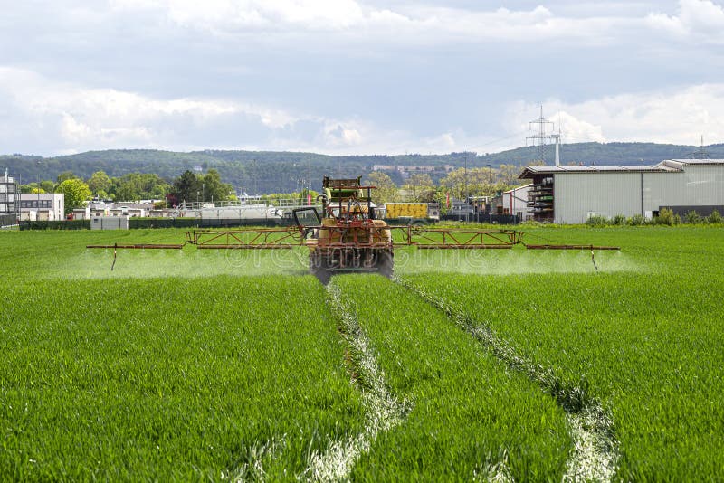 Spraying a Crop Field with a Tractor that Has a Tank with Spray Nozzles ...