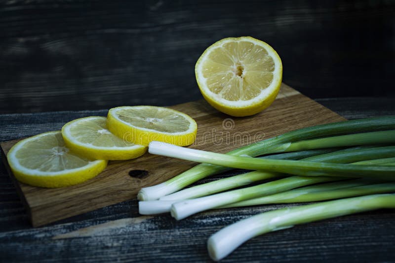 Spring Onions and Slicing Lemon on a Dark Wooden Background Stock Image ...