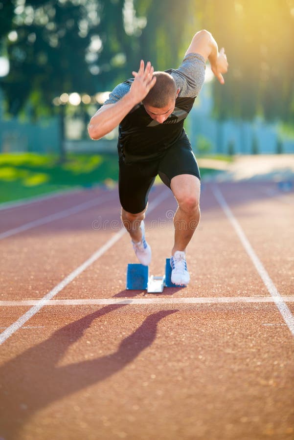 Sprinter Leaving Starting Blocks on the Running Track in Front of Big ...