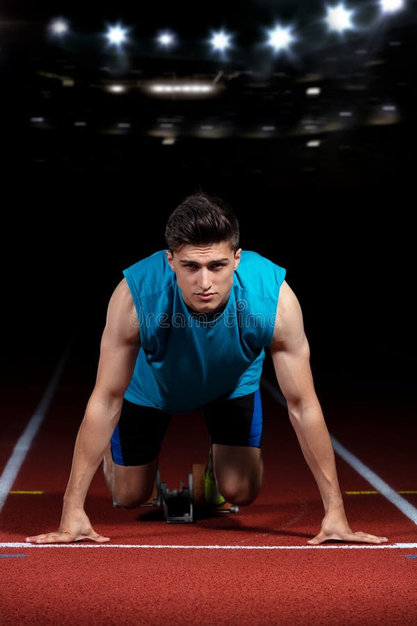 Sprinter Leaving Starting Blocks on the Running Track in Front of Big ...