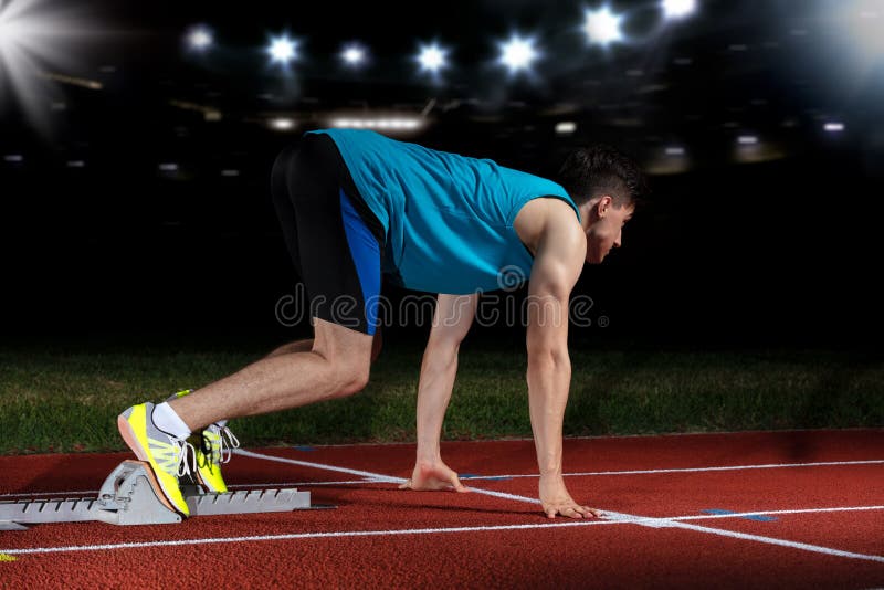 Sprinter Leaving Starting Blocks on the Running Track in Front of Big ...