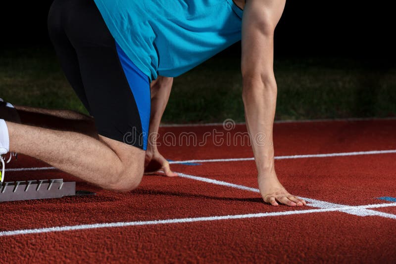 Sprinter Leaving Starting Blocks on the Running Track in Front of Big ...