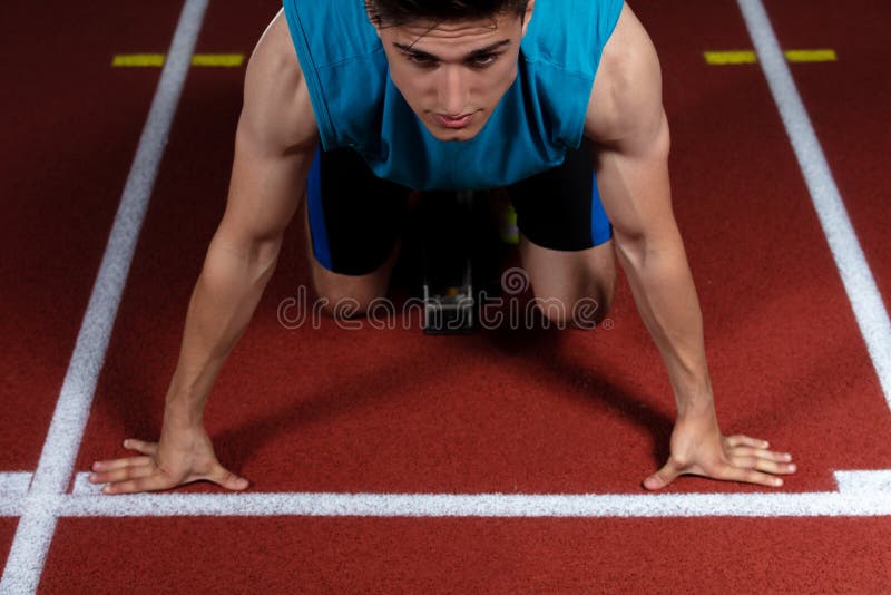 Sprinter Leaving Starting Blocks on the Running Track in Front of Big ...