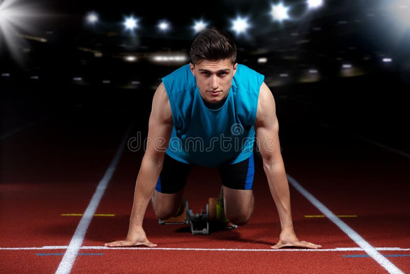 Sprinter Leaving Starting Blocks on the Running Track in Front of Big ...