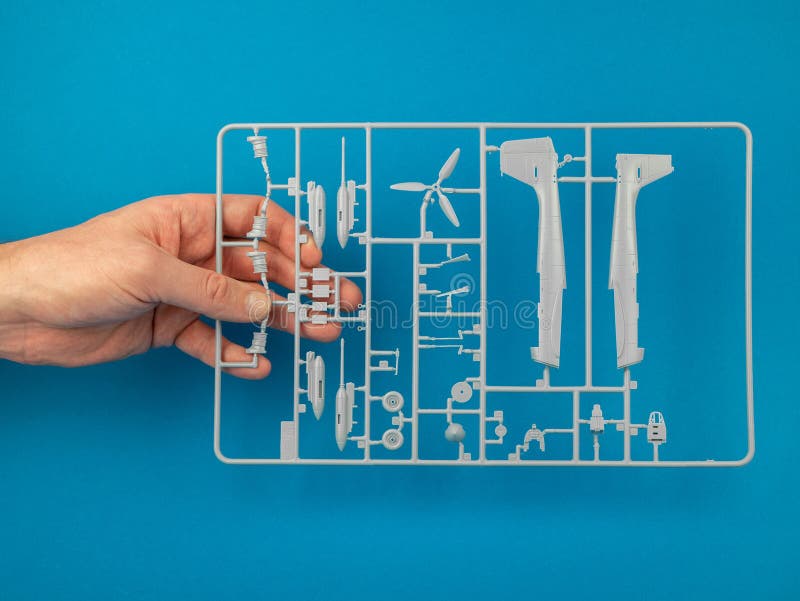 Sprue From A Plastic Model Kit In Hand On The Blue Background Parts Tree Of The Airplane Model