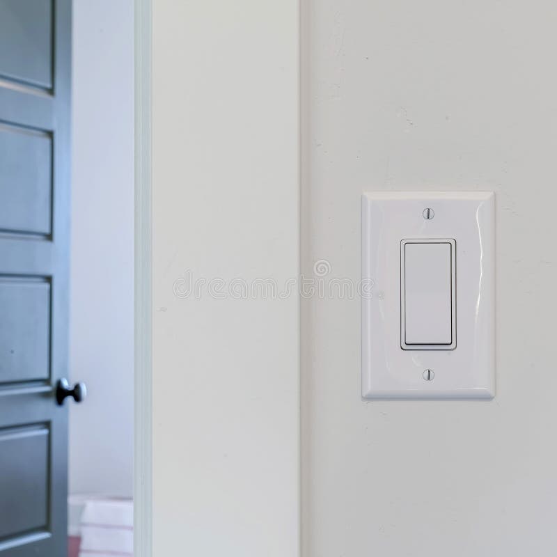 Square Electrical Rocker Light Switch on White Wall Against Blurry Door ...