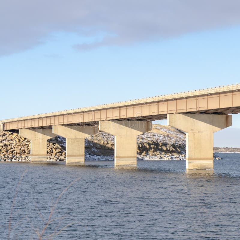 Square Stringer Bridge Spanning Over Calm Lake with View of Snowy Land ...