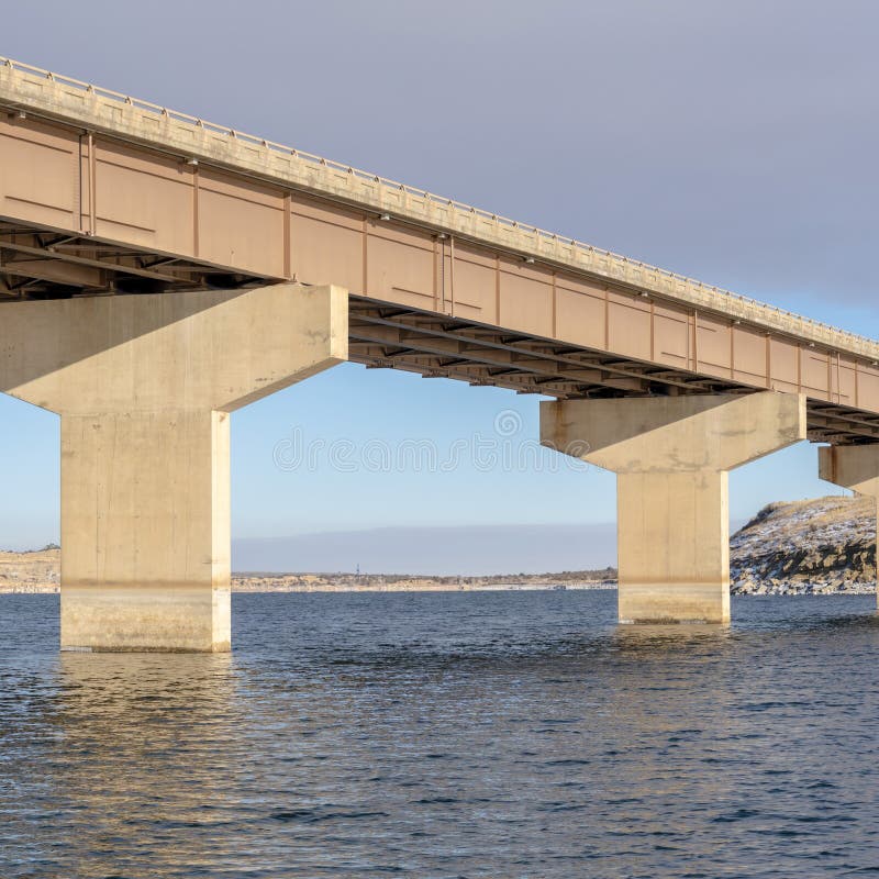 Square Stringer Bridge Spanning Over Calm Lake with View of Snowy Land ...
