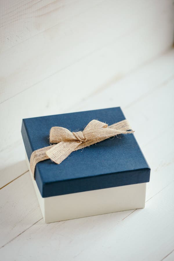 Square Gift Box with Blue Lid and Burlap Bow on White Wooden Background ...