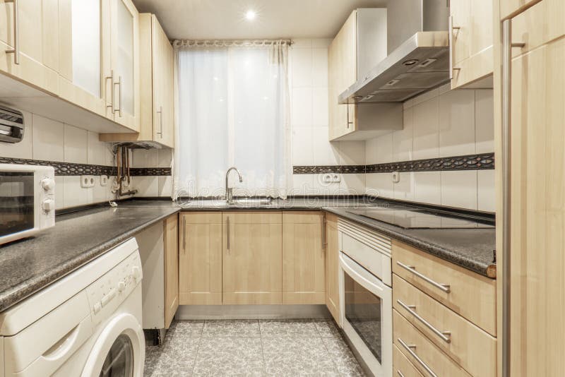 Square Kitchen with Light Wood Cabinets and Black Countertop Stock ...