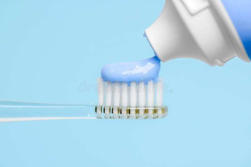 Squeezing Toothpaste Onto Electric Toothbrush on Light Blue Background ...