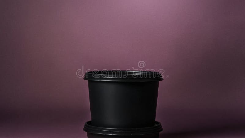 Stack of Black Plastic Containers Against a Deep Purple Background ...