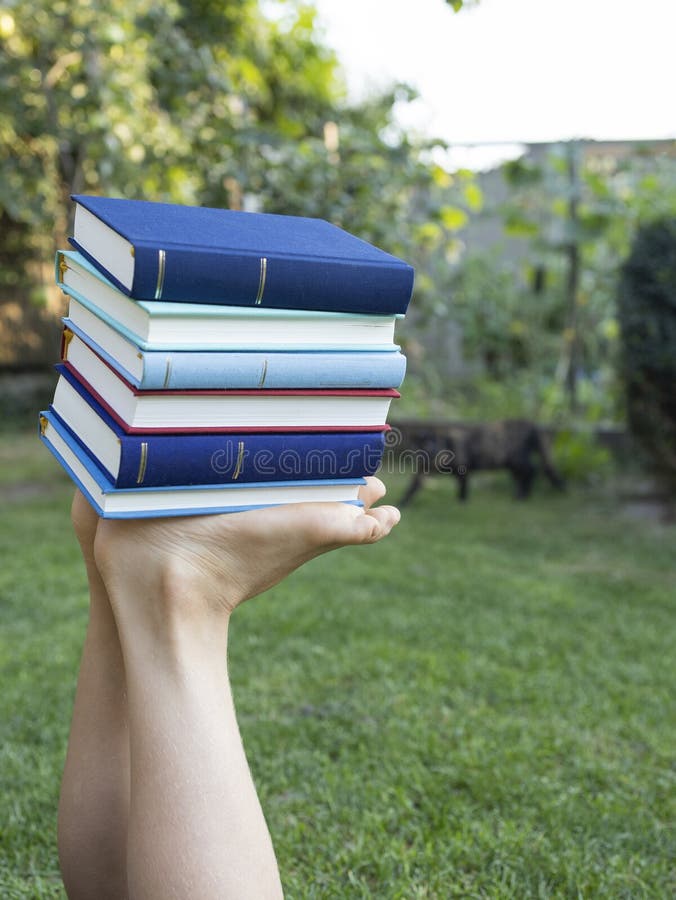 Stack of Books on Bare Feet of Child Lying on Grass. Reading Books ...