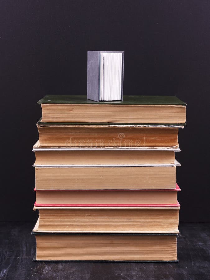 Stack of Books on a Black Background with Small Book on Top Stock Photo ...