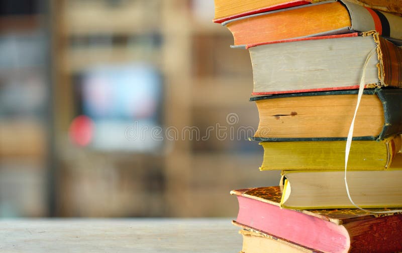 Stack of Books with Blurred Bookshelf and Computer Monitor in the ...