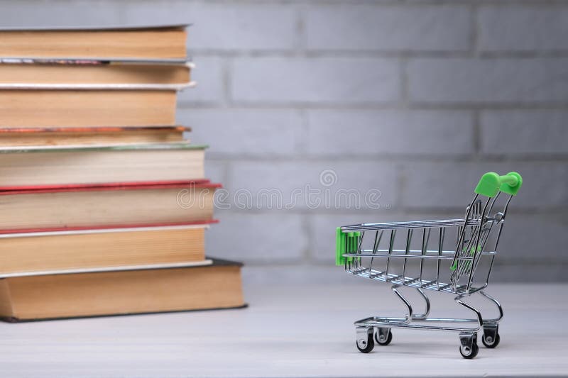 Stack with Books and Mini Shopping Cart on Table, Education Concept ...